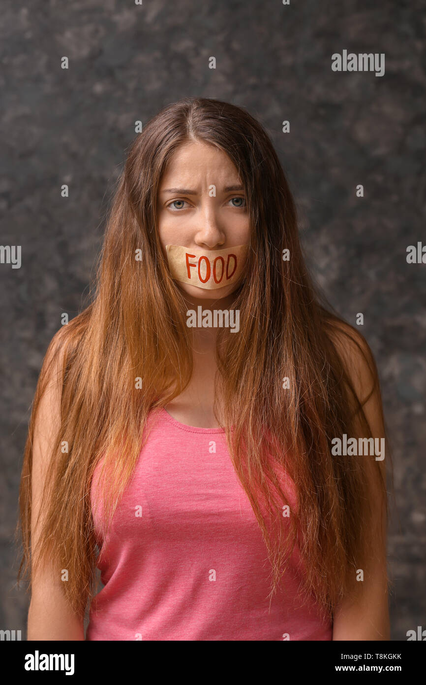 Woman with taped mouth on grey background. Diet concept Stock Photo - Alamy