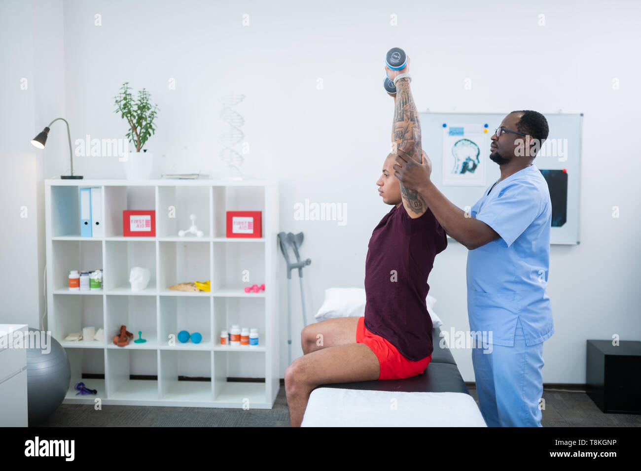 Man sitting and raising hands with barbells visiting therapist Stock ...