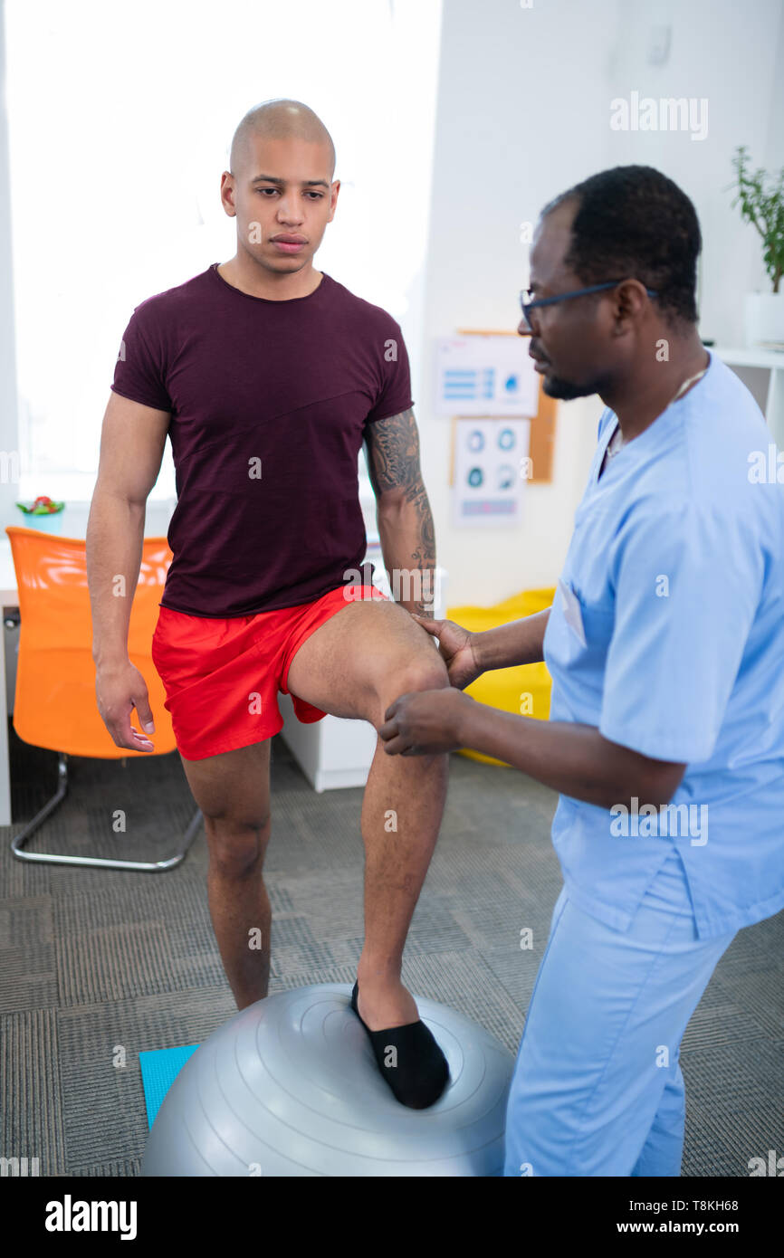 Therapist examining knee of bodybuilder after serious injury Stock ...