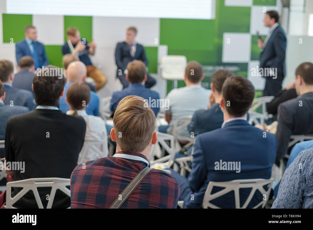 Audience listens to the lecturer at the business conference, back view ...
