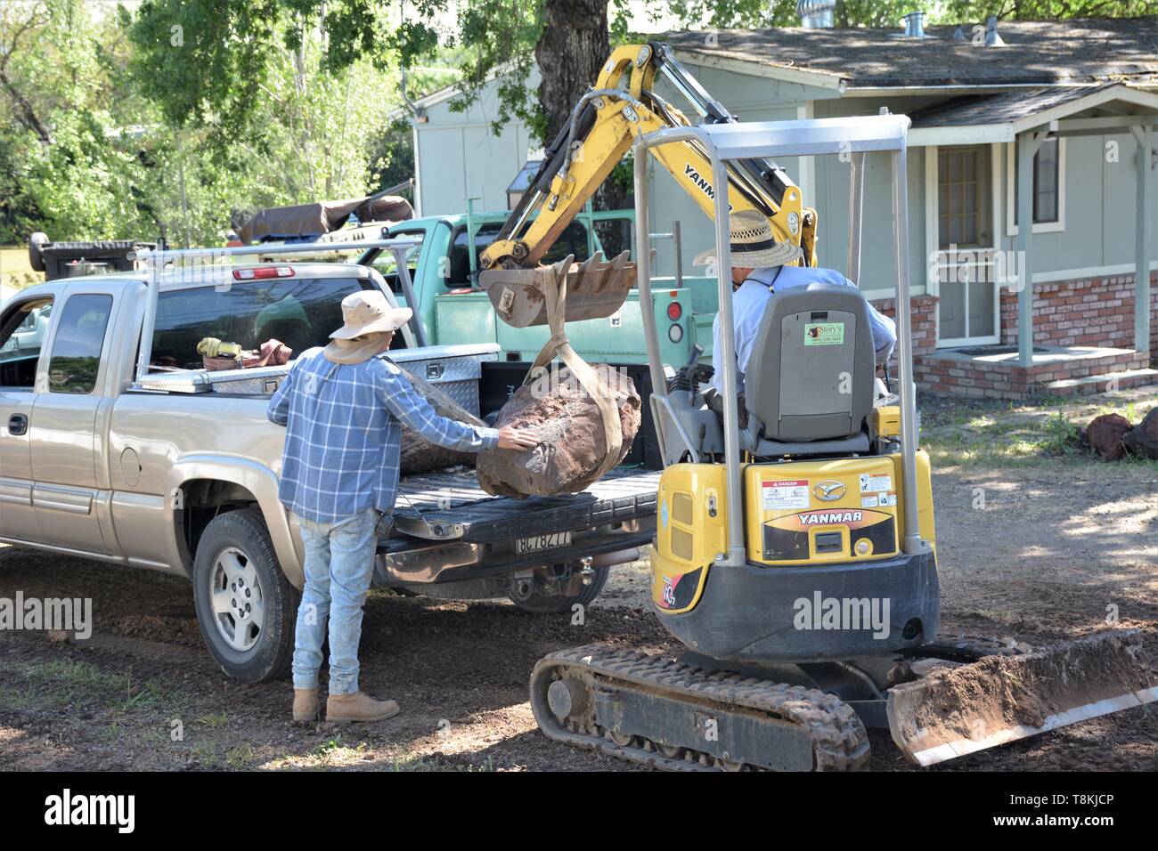 Moving rocks and installing piping for landscaping, by Mexican laborers ...