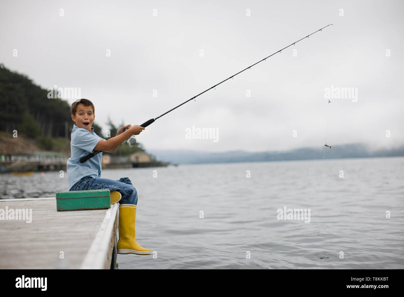 Portrait of a surprised boy fishing off the side of a jetty with a ...