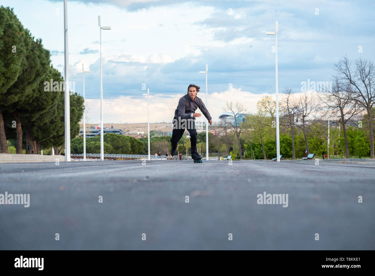 From below young cool male in sportswear riding on roller skates very ...