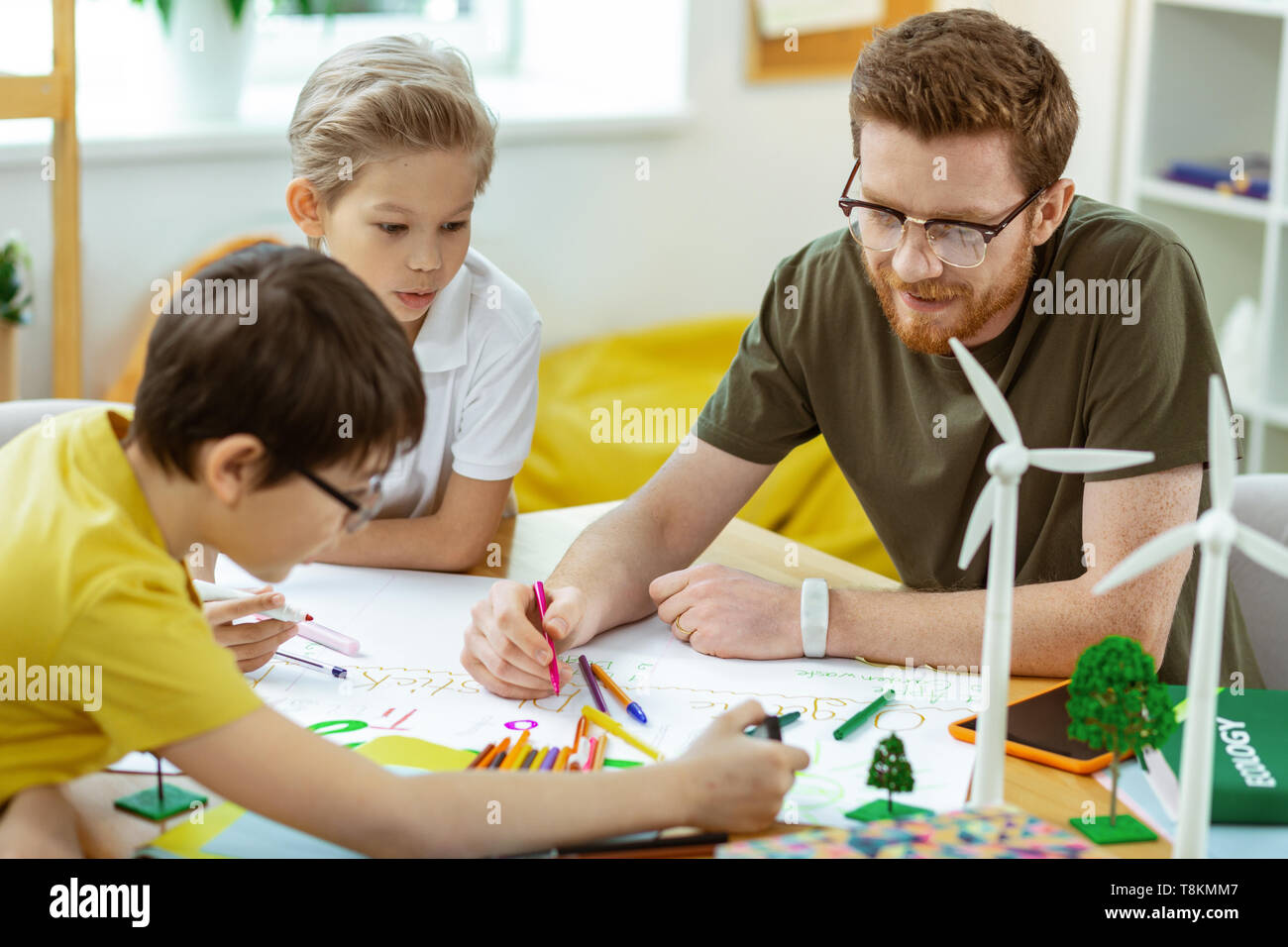 Ginger good-looking teacher with red beard writing down on the paper ...