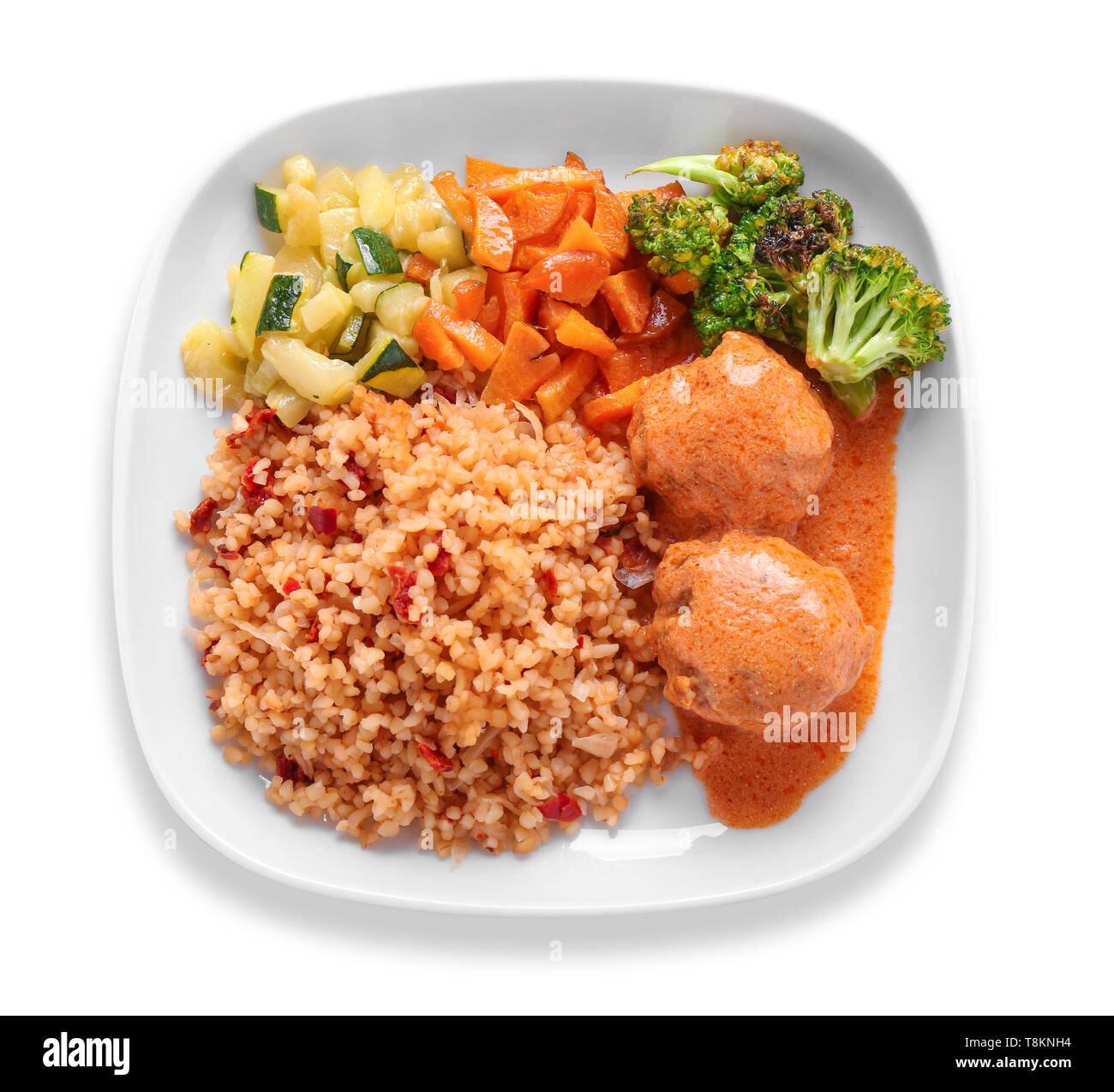 Tasty boiled rice with meatballs and vegetables on plate, isolated on ...