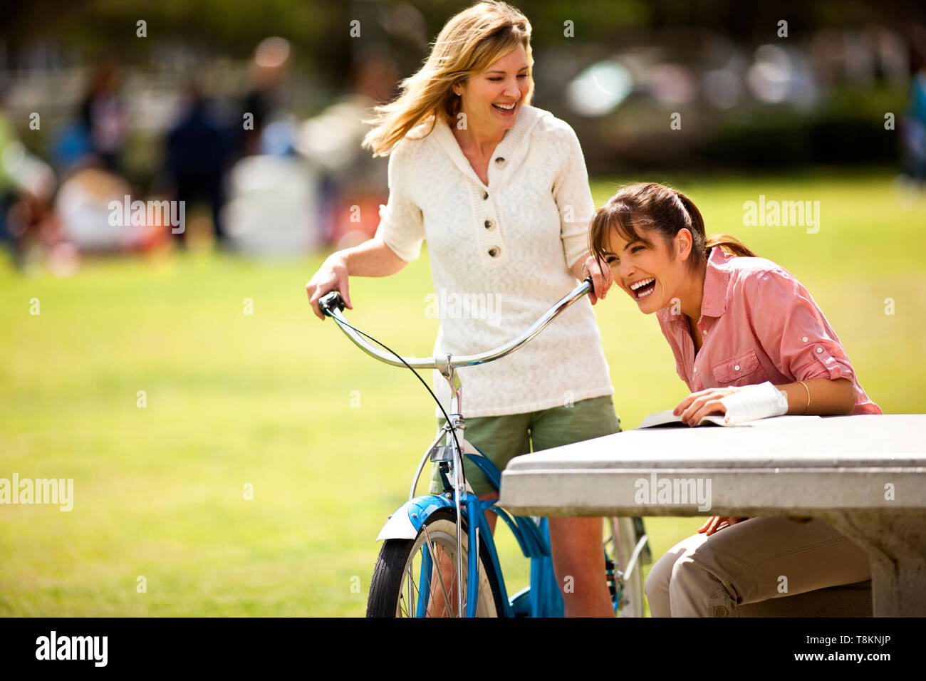 Two female friends bump into each other at the park Stock Photo - Alamy