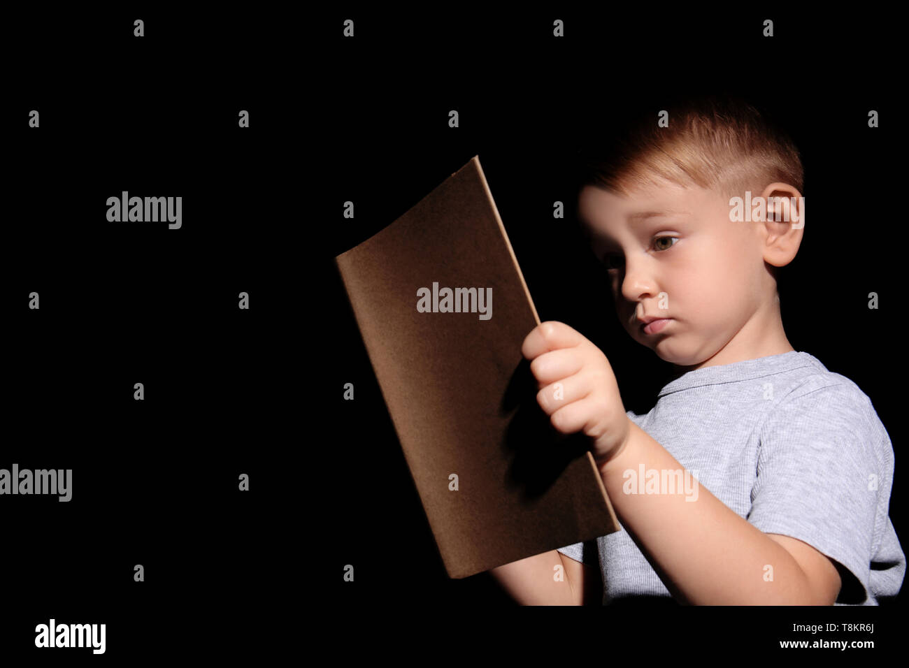 Shocked little boy reading book on dark background Stock Photo - Alamy