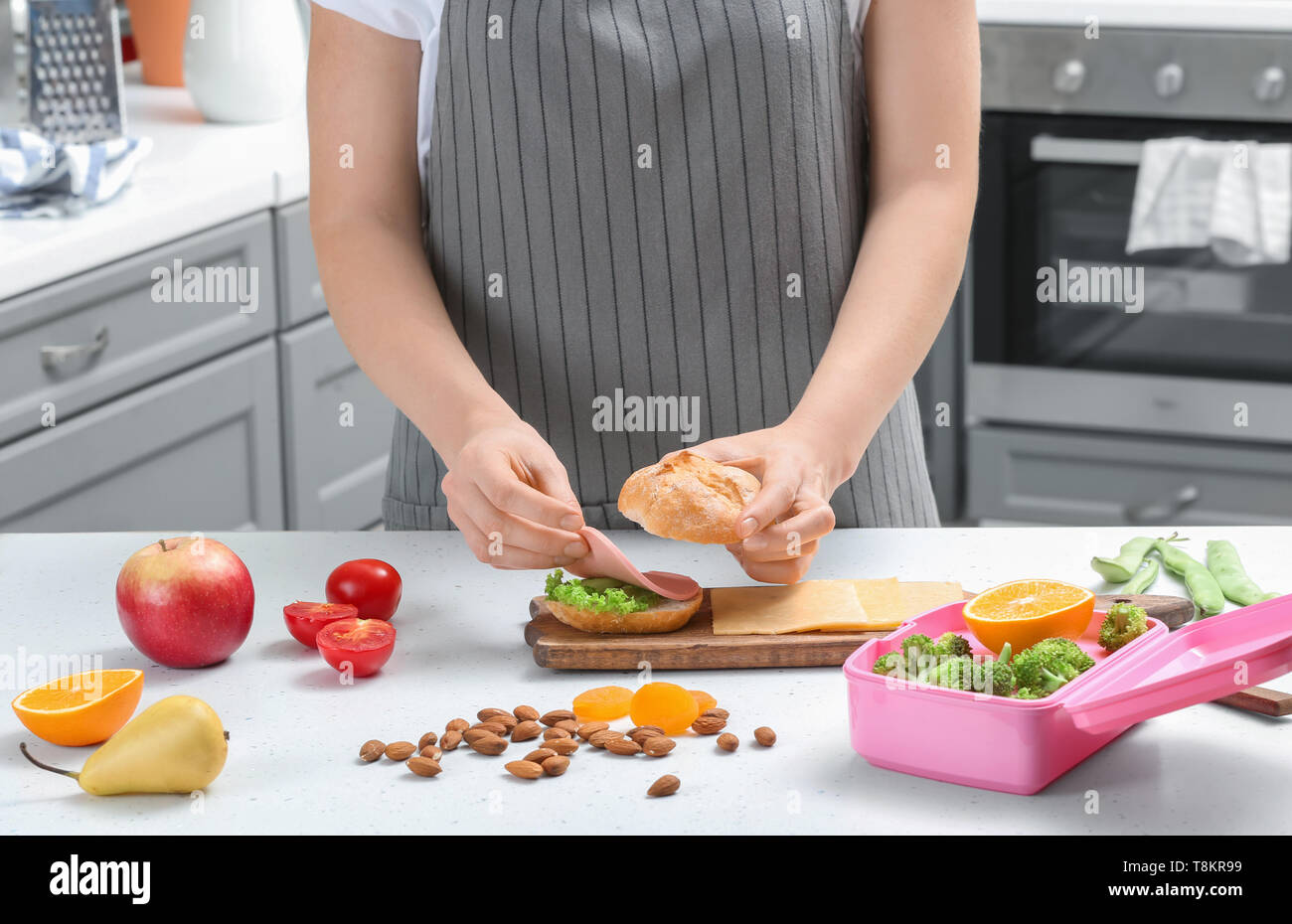 Mother making sandwich for school lunch at table in kitchen Stock Photo ...