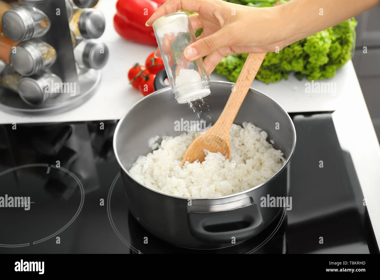 Woman salting boiled rice in kitchen Stock Photo - Alamy