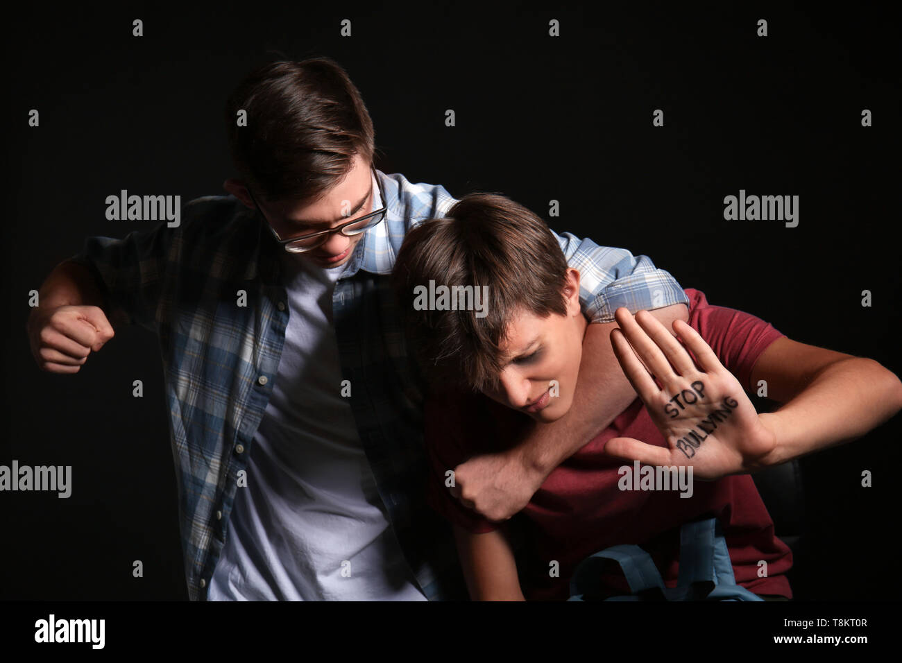 Boy with text STOP BULLYING written on hand and aggressive teenager ...
