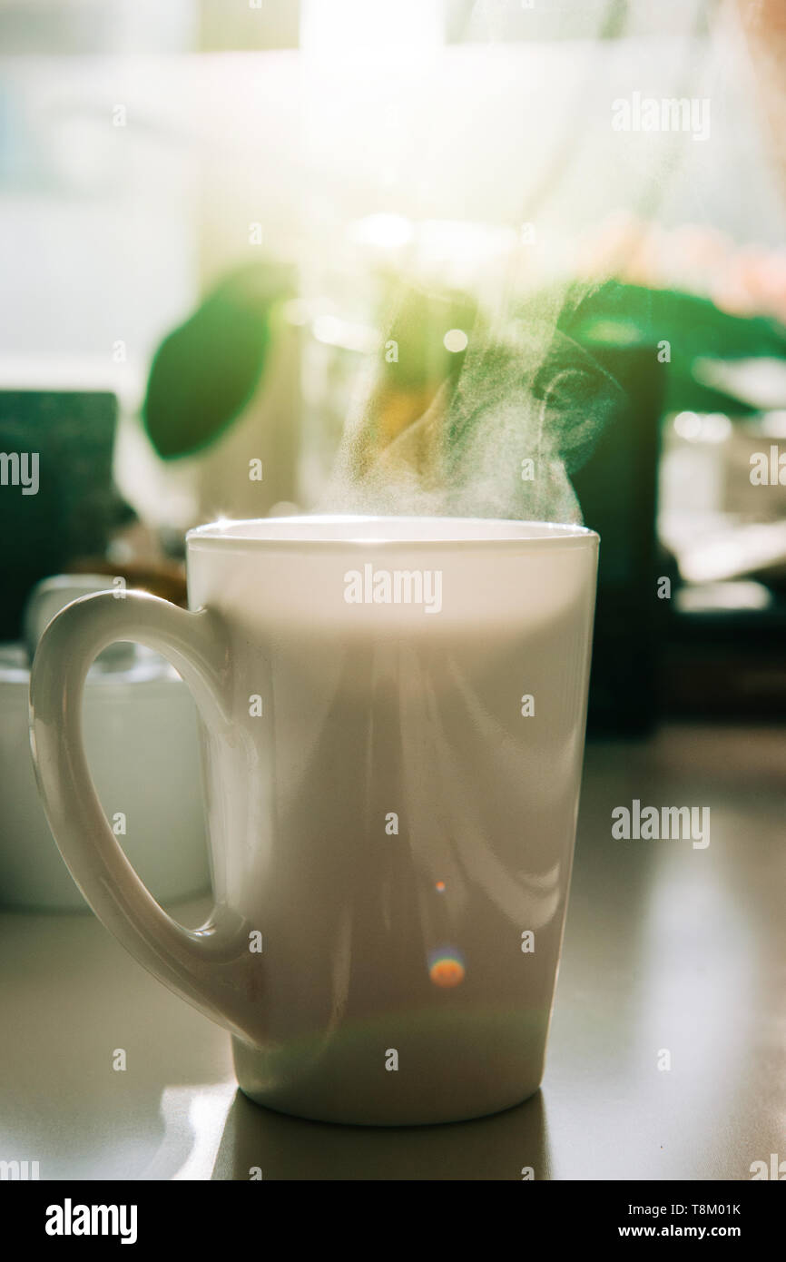 White coup of tea coffee on table with tiny particles of the steam ...