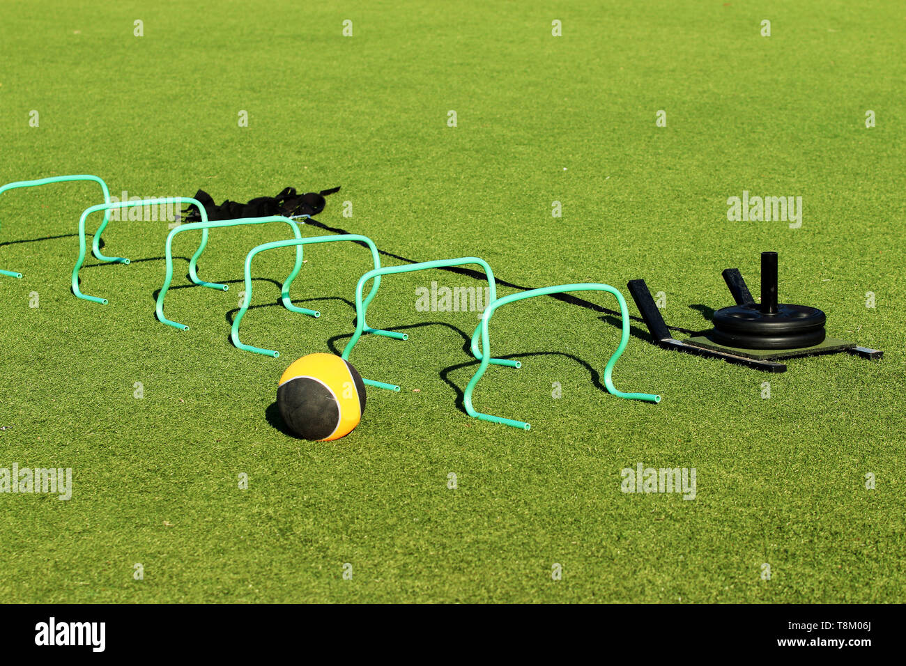 A medicine ball, banana hurdles and a weighted sled on a green turf field Stock Photo - Alamy