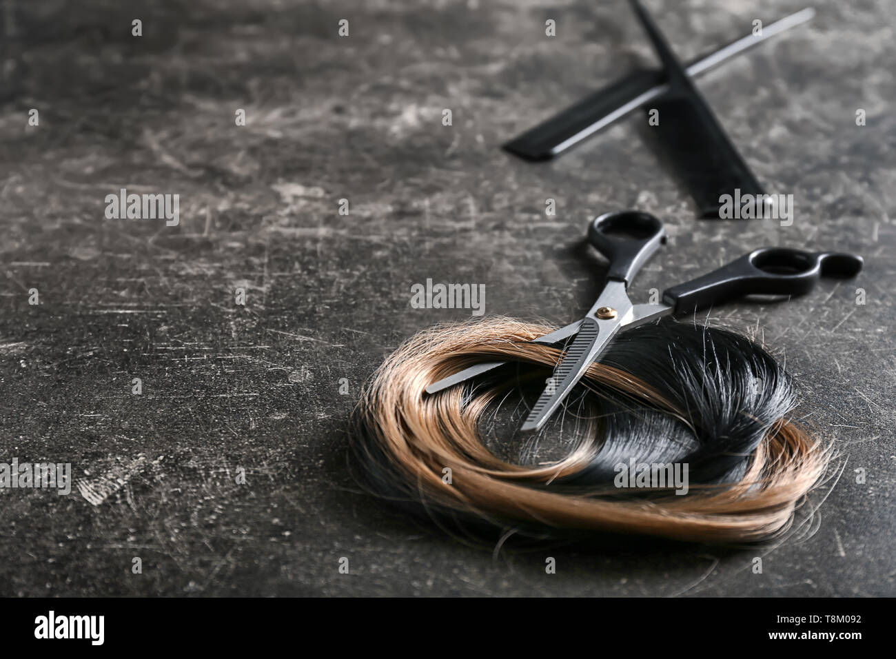 Professional hairdresser's scissors with strands of hair on dark ...