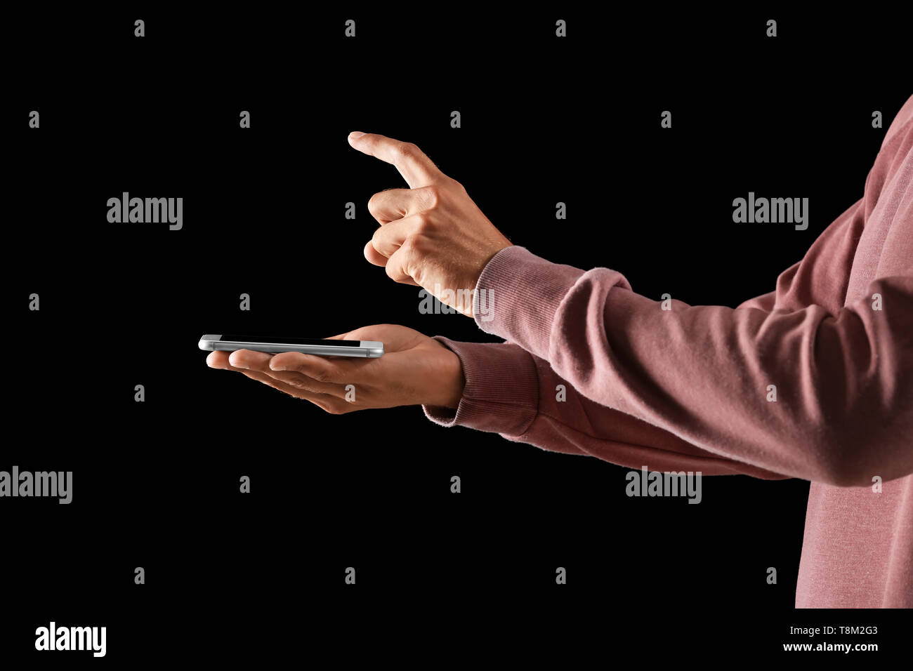 Young man with mobile phone using virtual screen on dark background ...