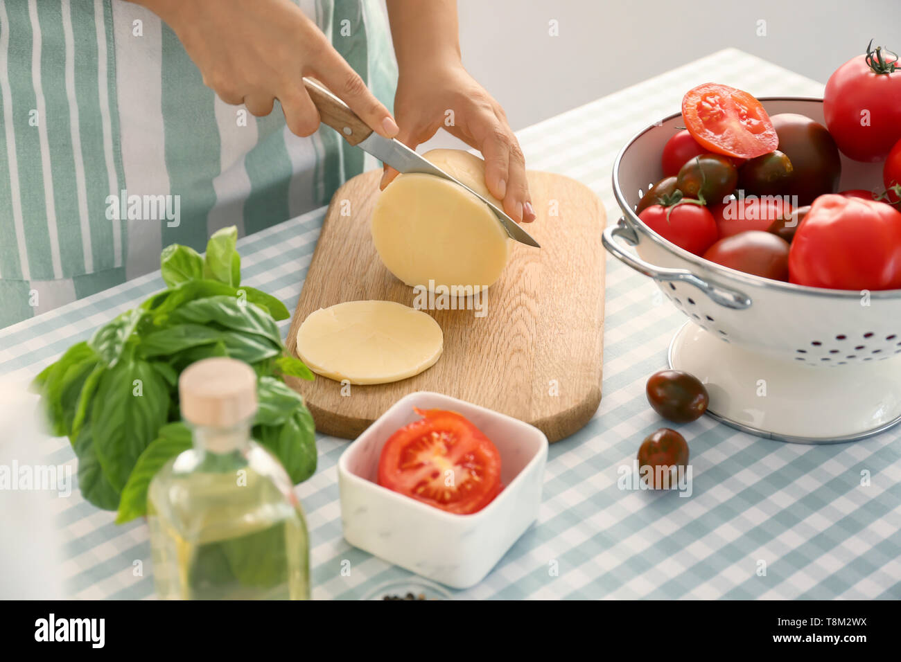 Woman cutting mozzarella cheese for caprese on wooden board Stock Photo ...