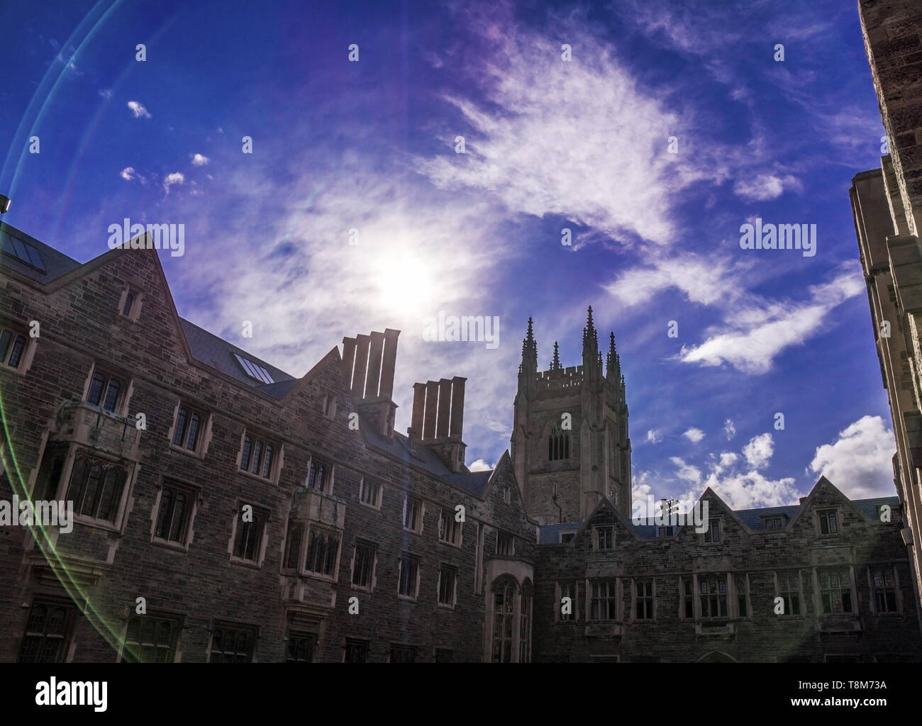 Gothic architecture building in front of bright blue sky with shiny sun ...