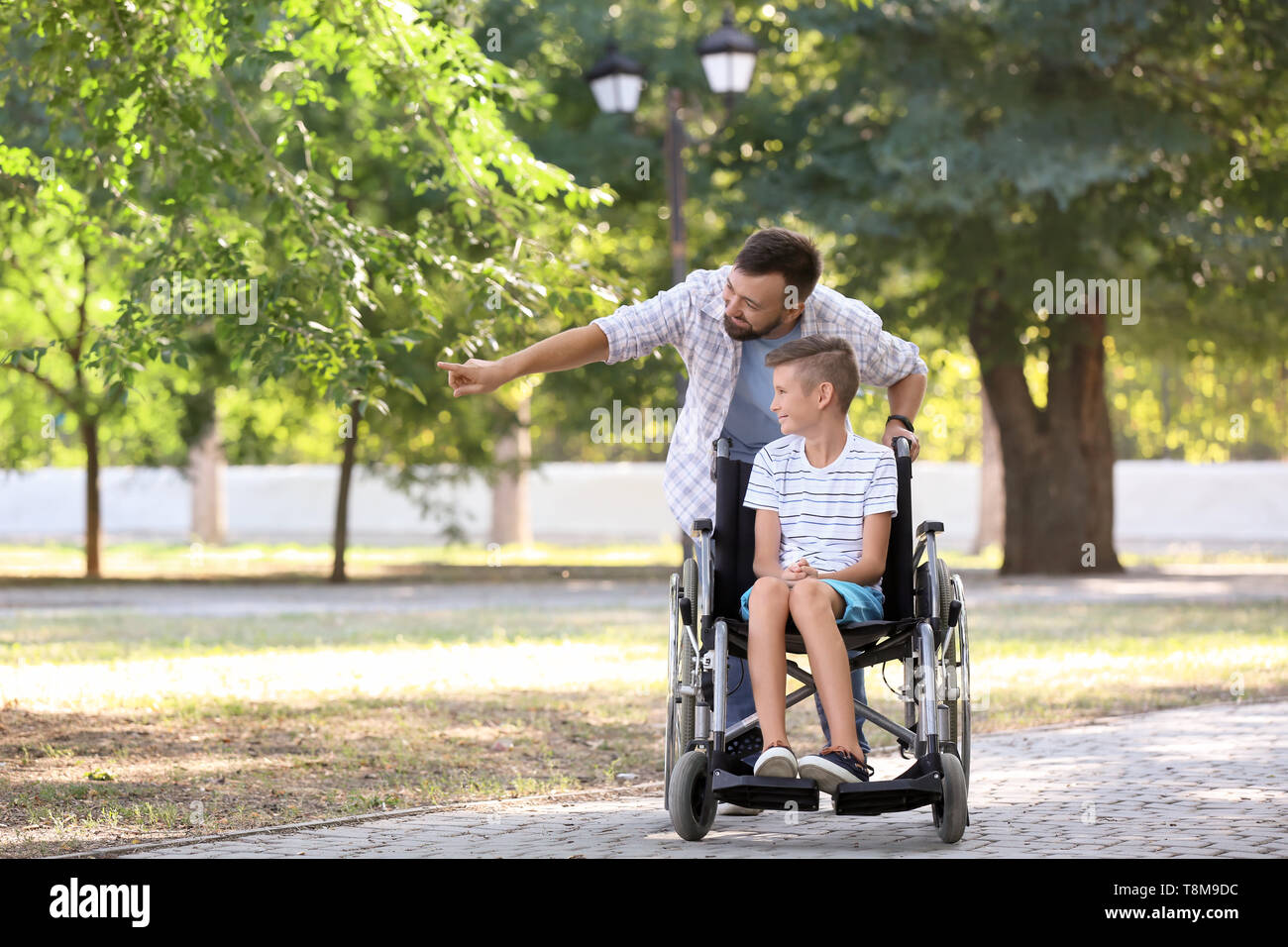 Teenage boy in wheelchair with his father outdoors Stock Photo - Alamy