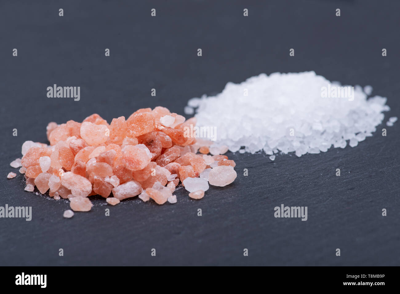 Piles of Coarse Sea Salt and Himalayan Pink Salt on dark background ...