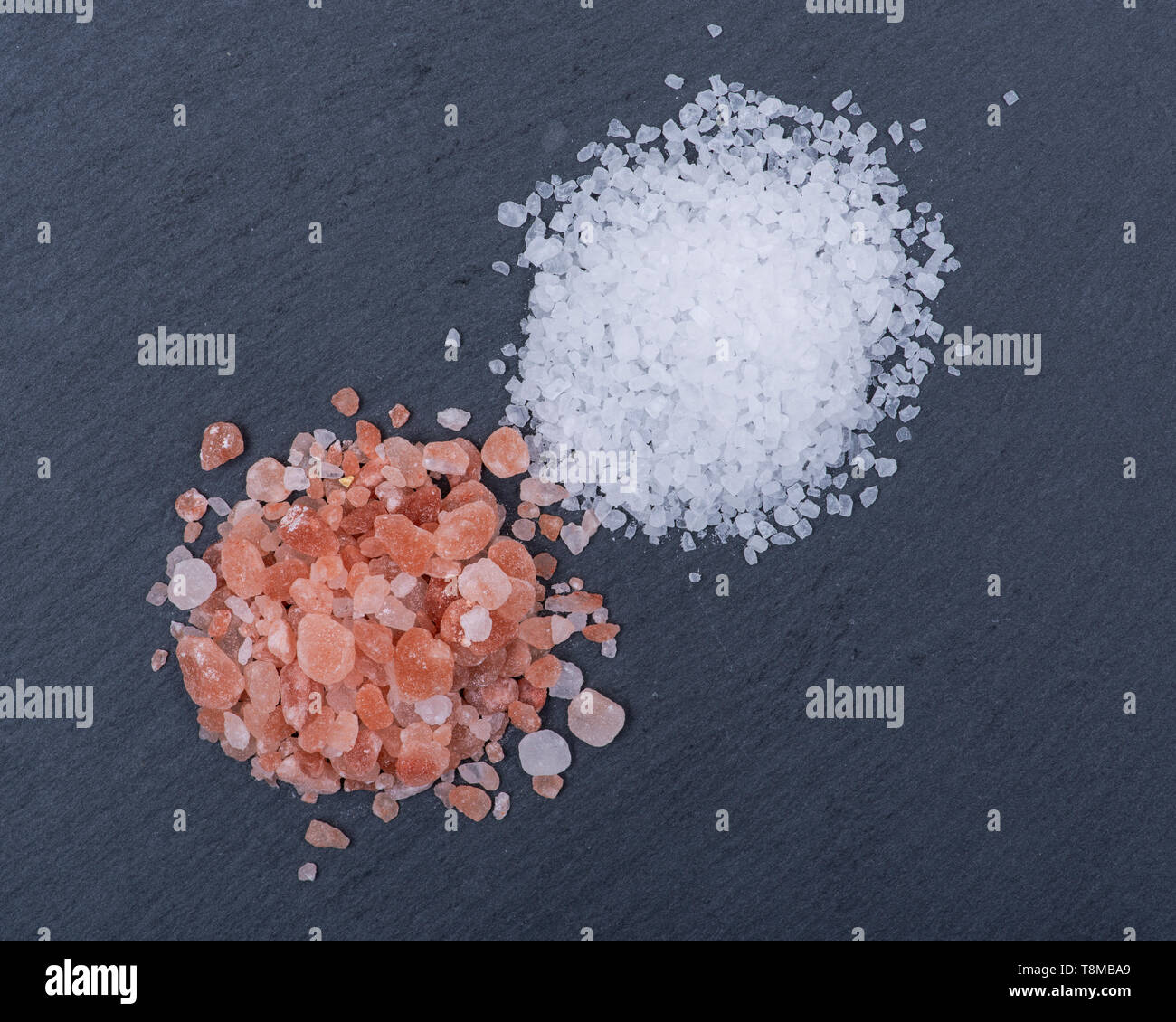 Piles of Coarse Sea Salt and Himalayan Pink Salt on dark background ...