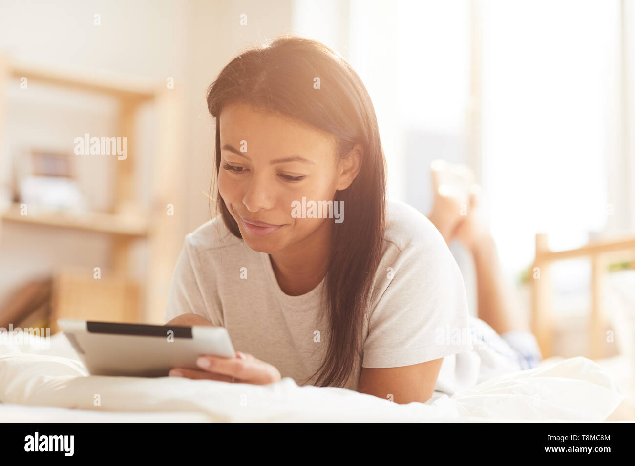Mixed Race Woman Using Tablet on Bed Stock Photo - Alamy