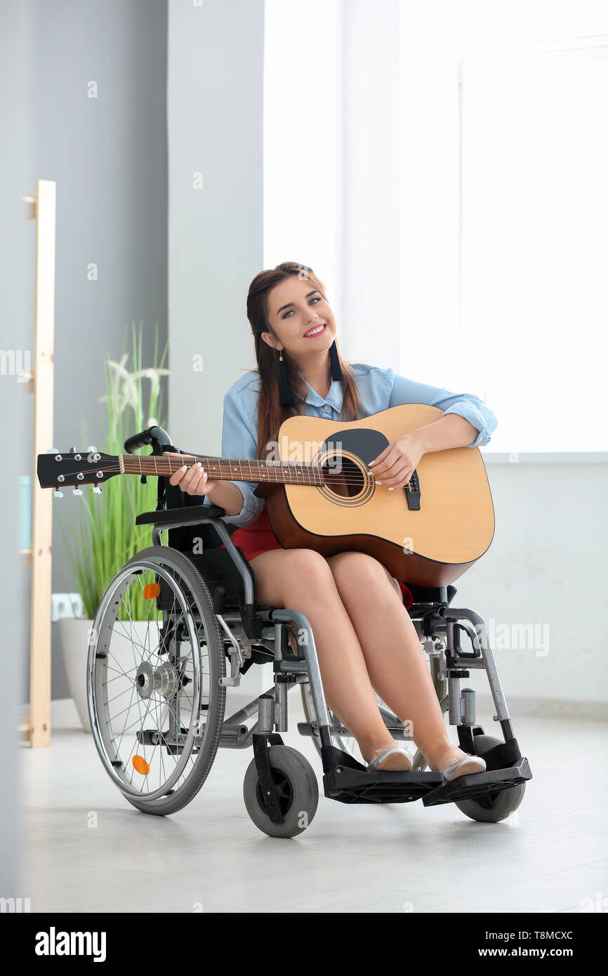 Beautiful young musician in wheelchair playing guitar at home Stock ...