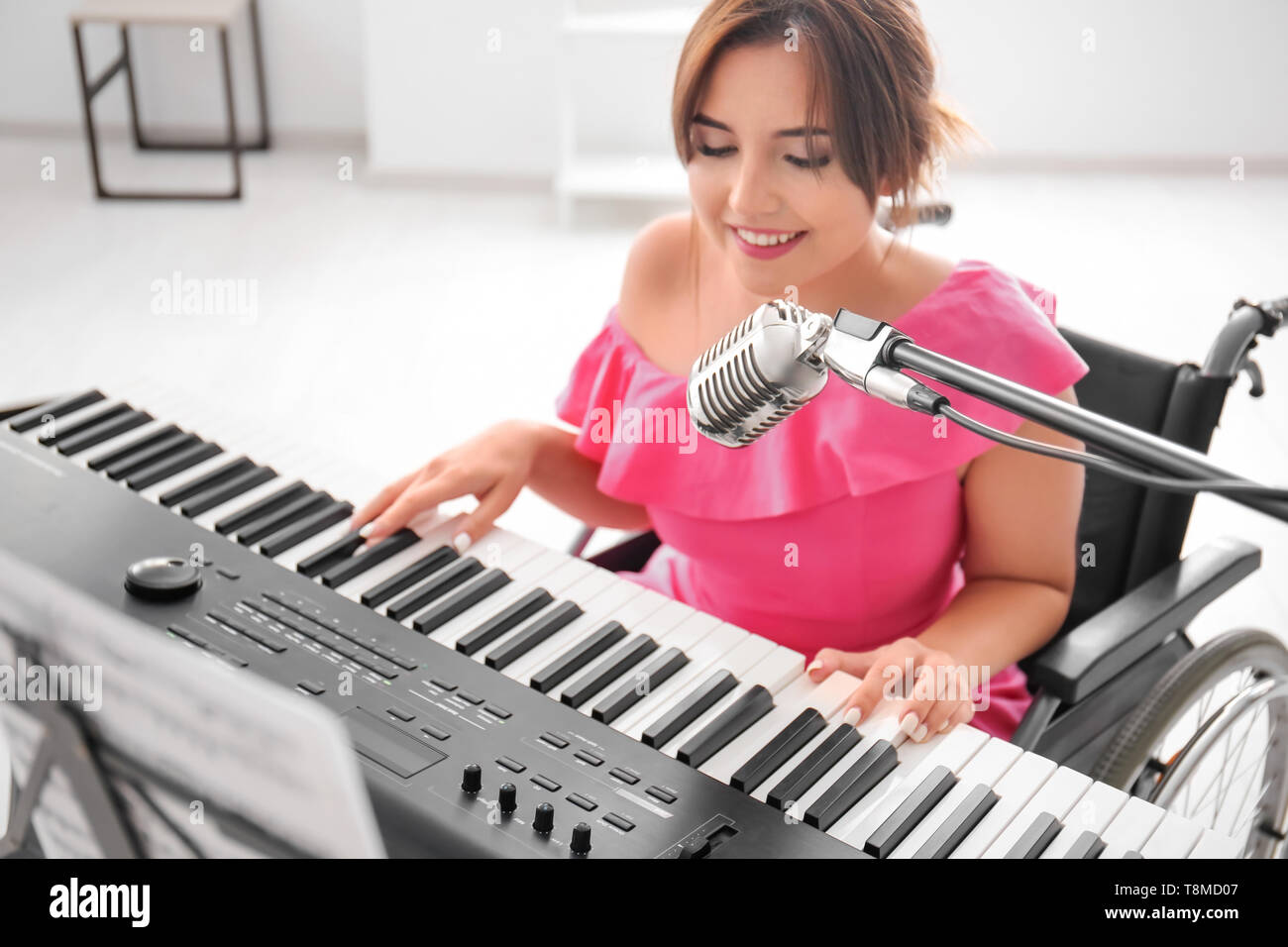 Beautiful young musician in wheelchair playing synthesizer and singing ...