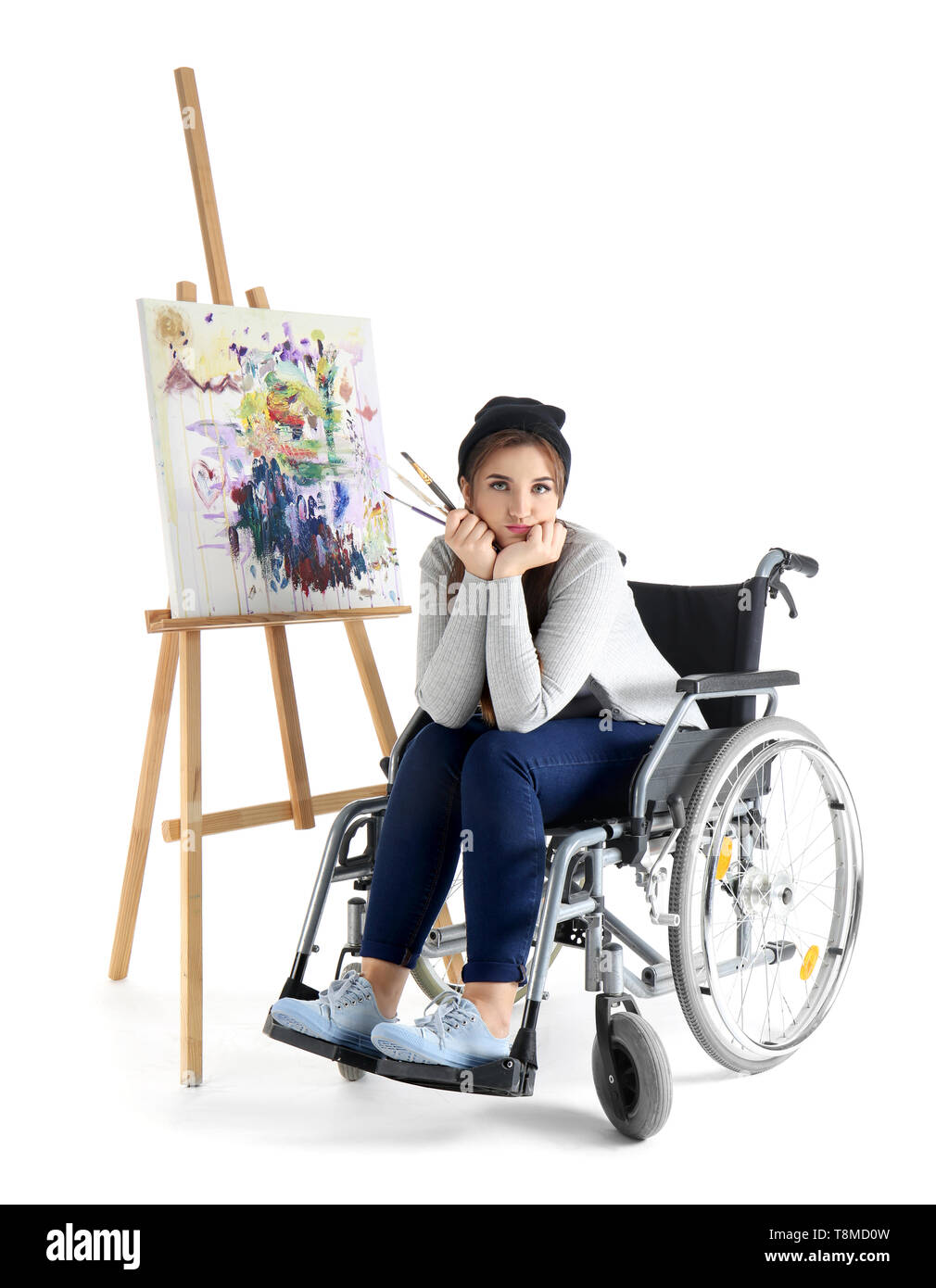 Young female artist in wheelchair painting picture on white background ...