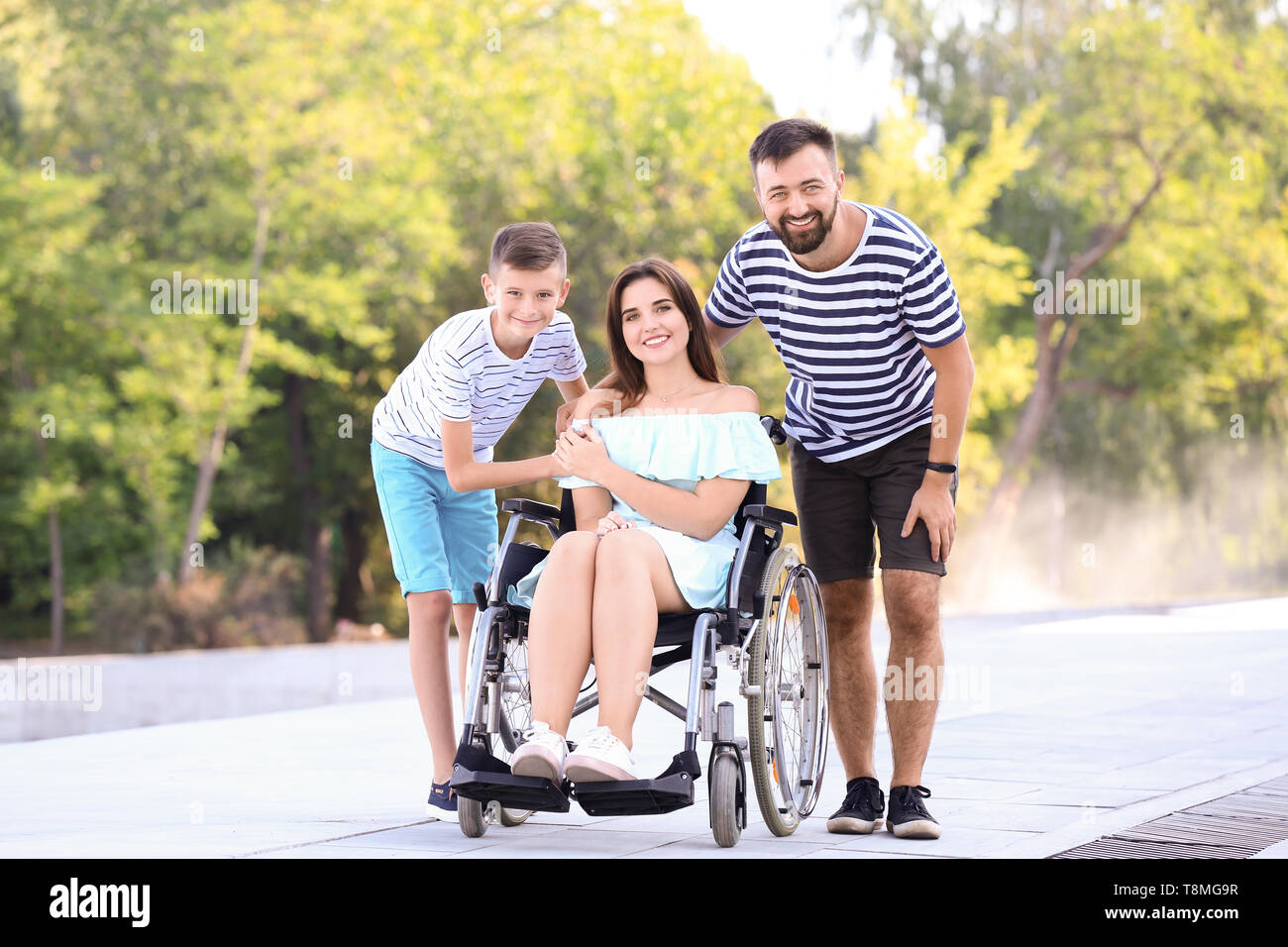 Young woman in wheelchair with her family walking outdoors Stock Photo ...