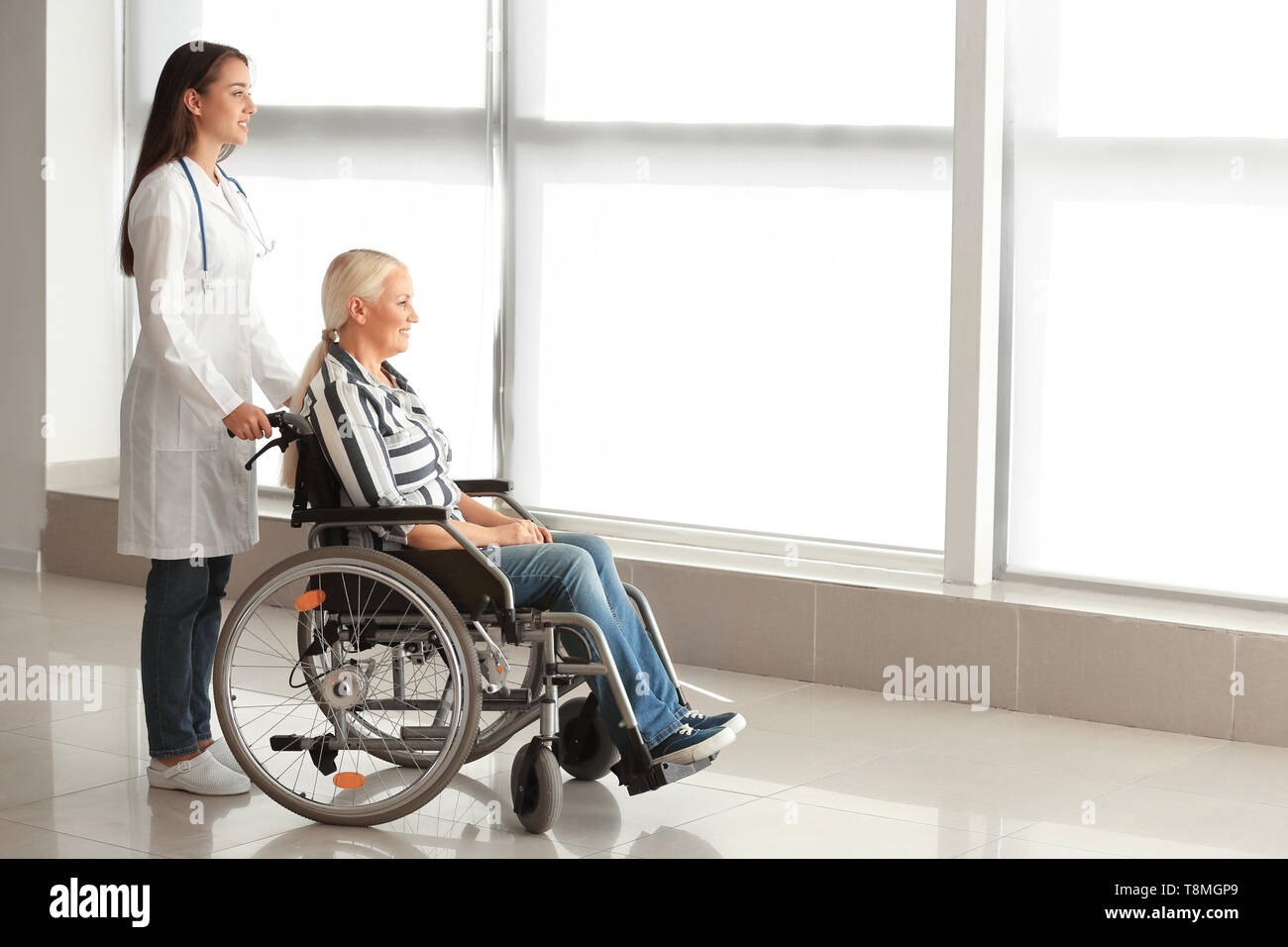 Handicapped mature woman with young female doctor in clinic Stock Photo ...