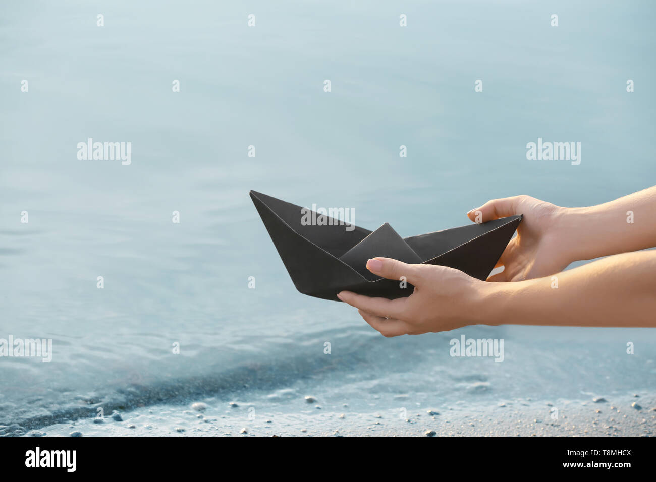 Woman holding origami boat near river Stock Photo - Alamy