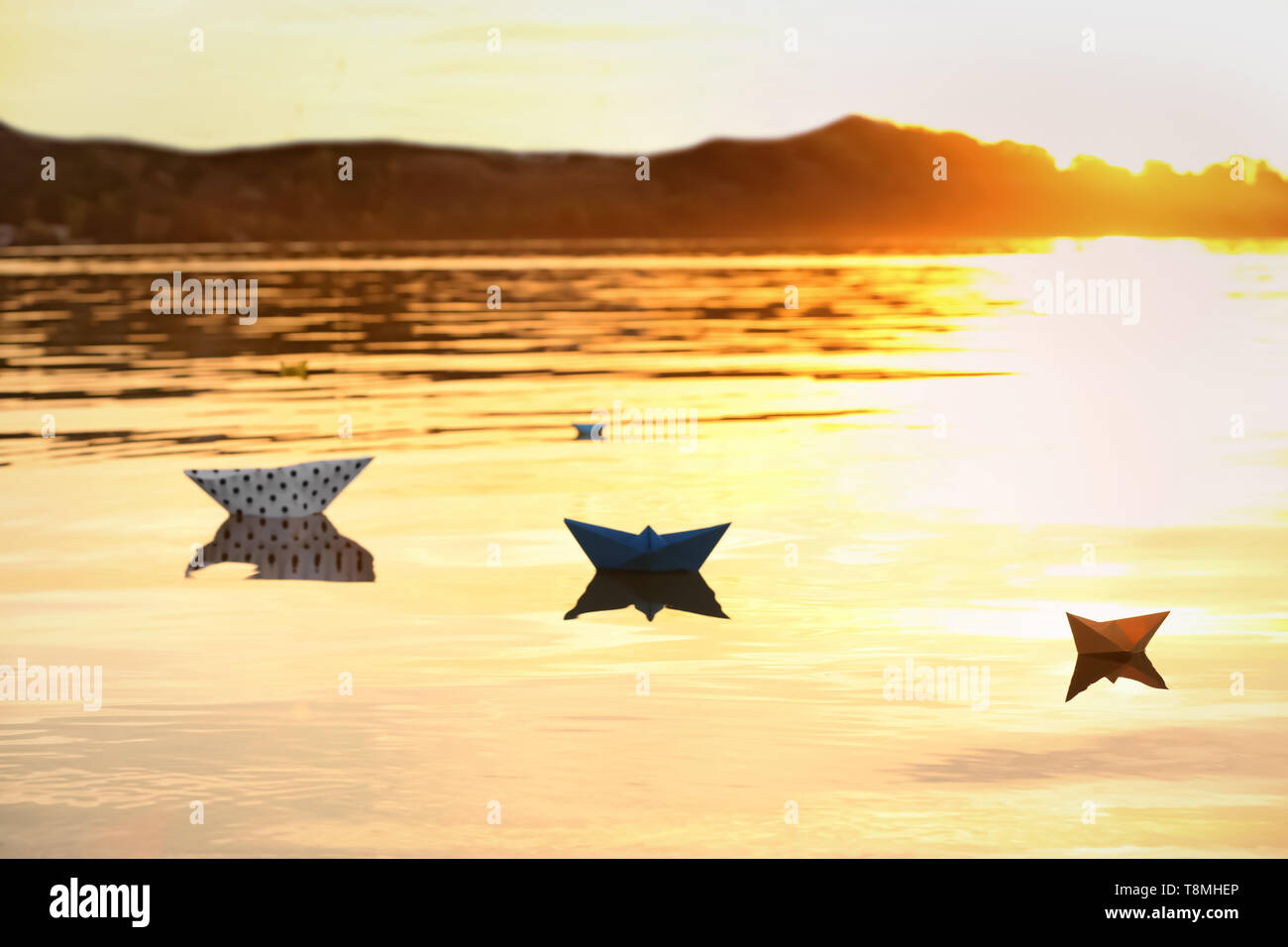 Origami boats on water surface at sunset Stock Photo - Alamy