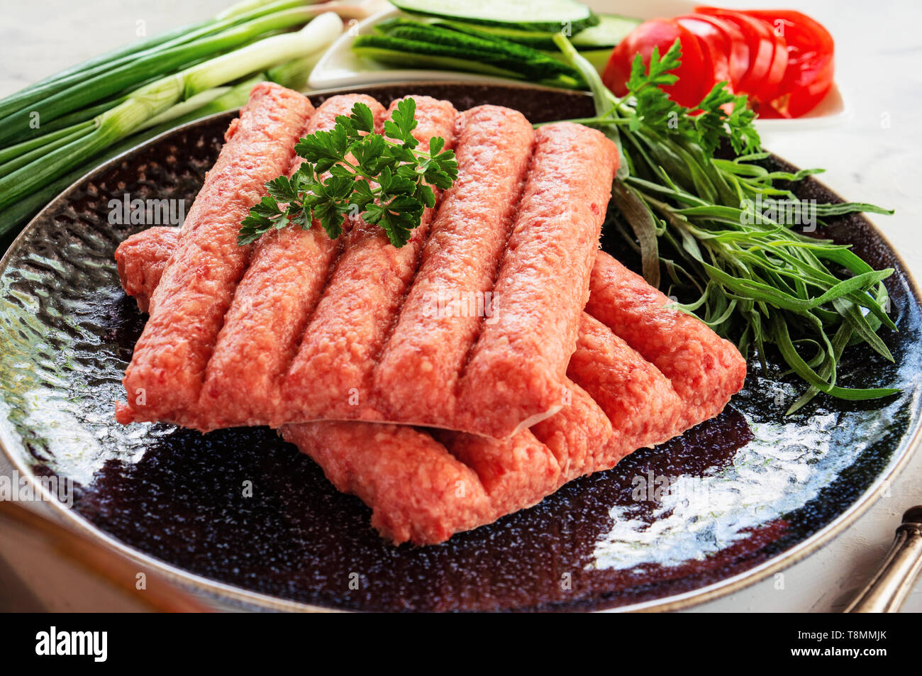 Chevapchichi is a national Balkan dish. Close up a row of fresh raw ...