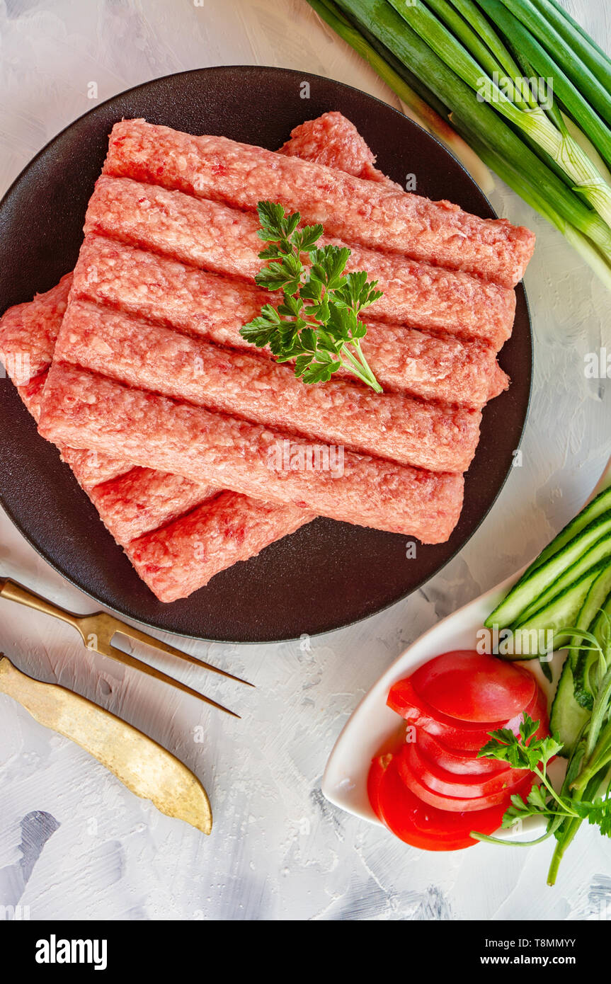 Chevapchichi is a national Balkan dish. Close up a row of fresh raw ...