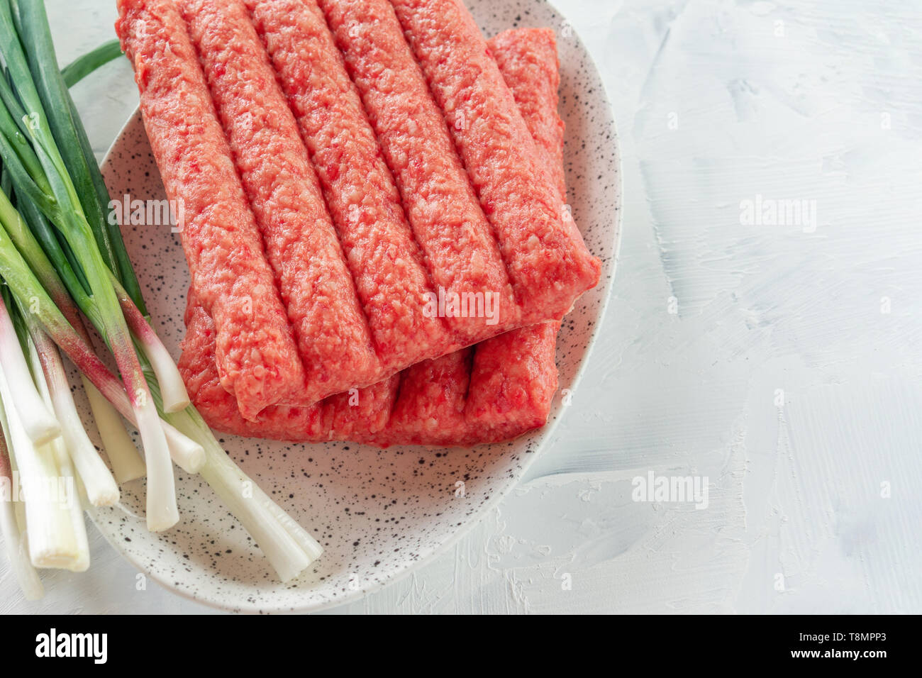 Chevapchichi is a national Balkan dish. Close up a row of fresh raw ...