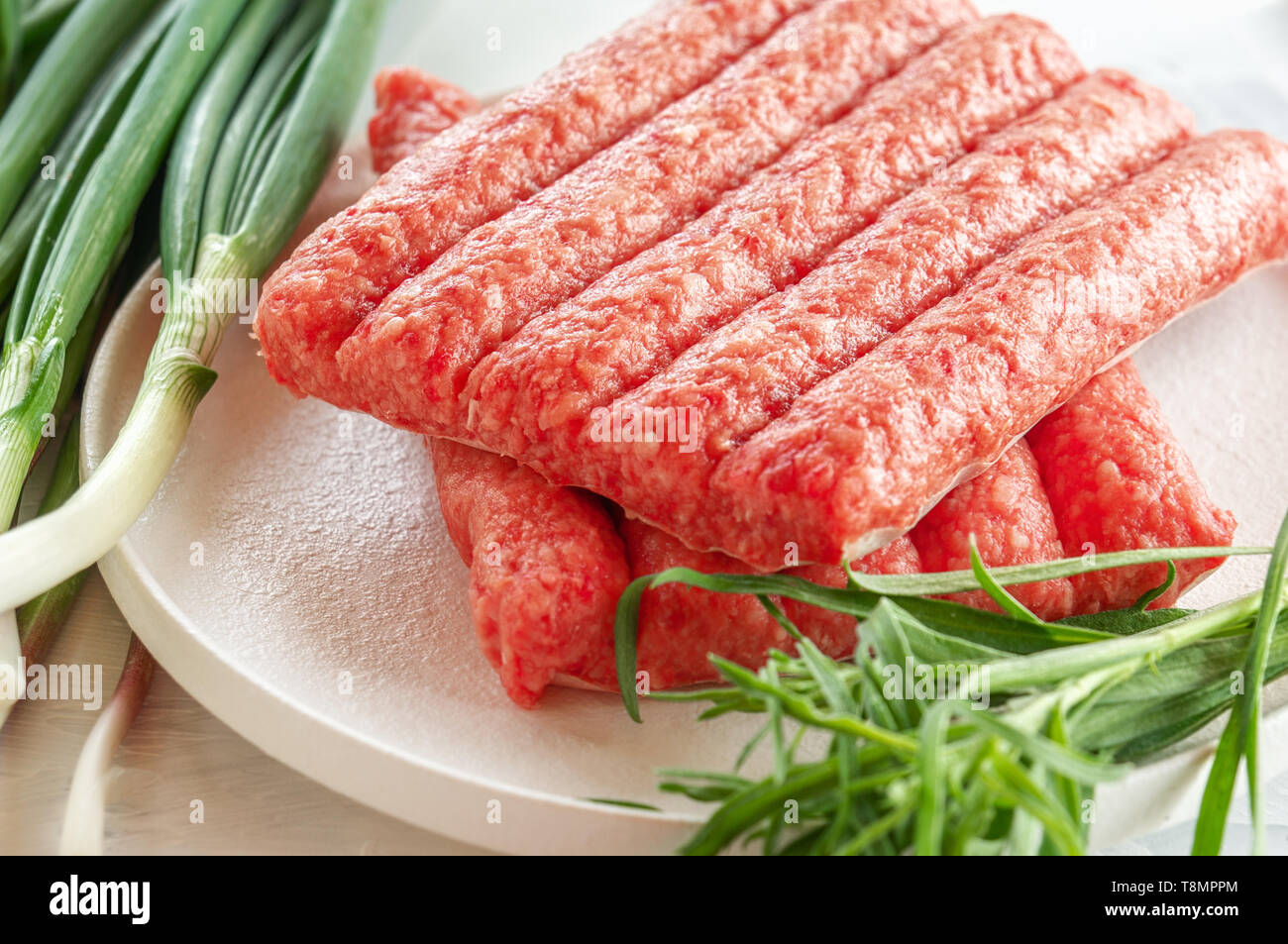 Chevapchichi is a national Balkan dish. Close up a row of fresh raw ...