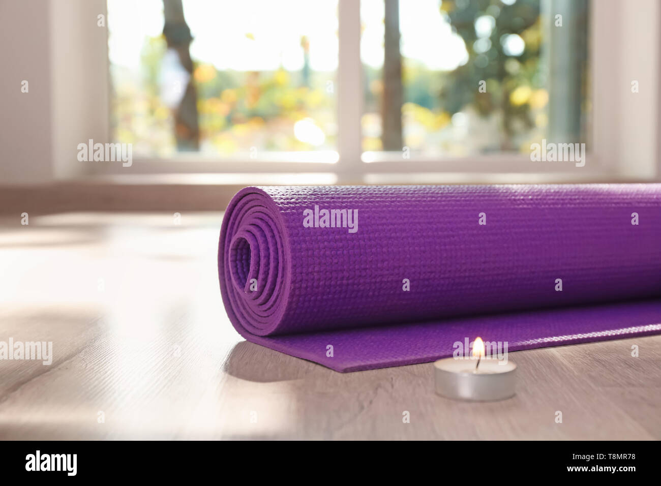 Yoga mat and burning candle on floor Stock Photo - Alamy