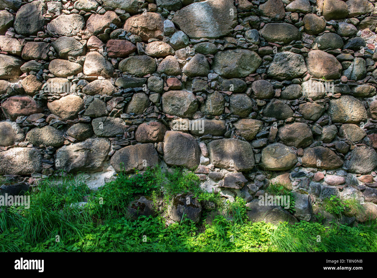 beautiful ancient stone brick wall with green grass below Stock Photo ...