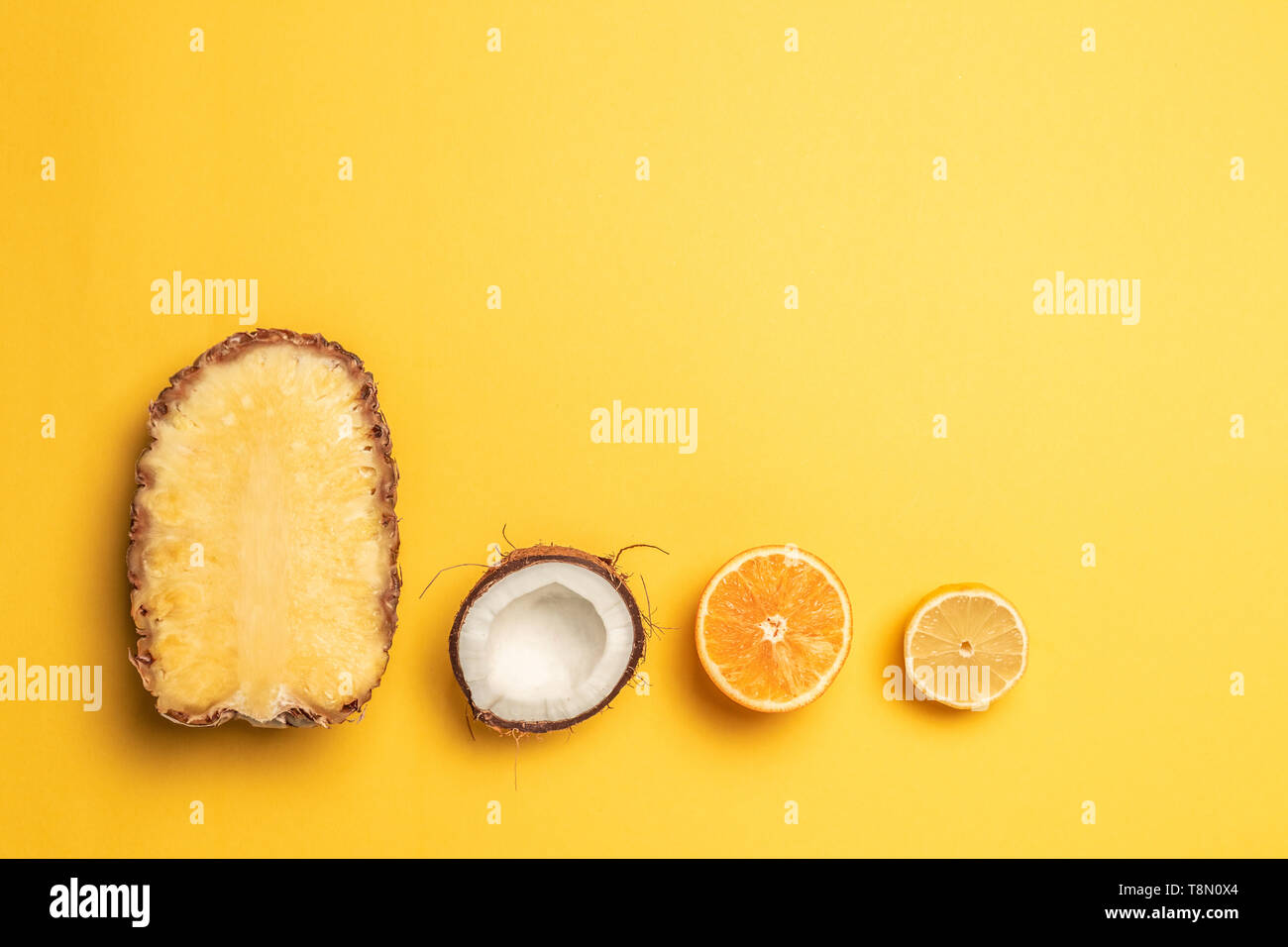 Tropical fruit flat lay with pineapple, oranges, lemon and coconut on a ...