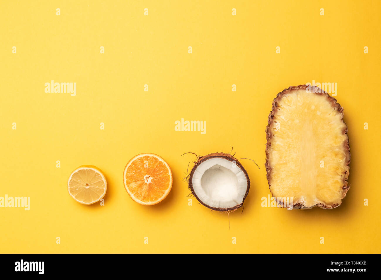 Tropical fruit flat lay with pineapple, oranges, lemon and coconut on a ...