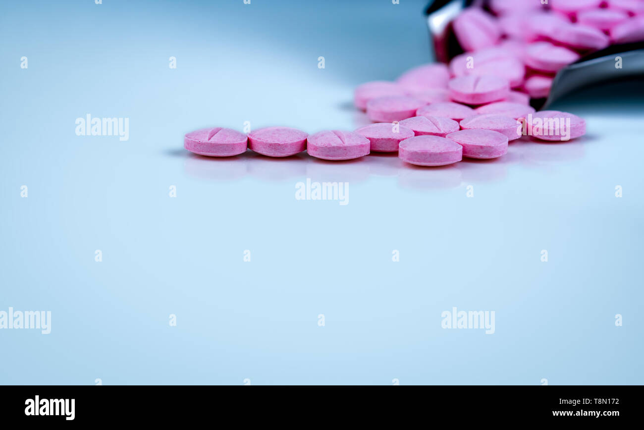 Pink tablets pills on blurred background of drug tray. Pharmaceutical ...