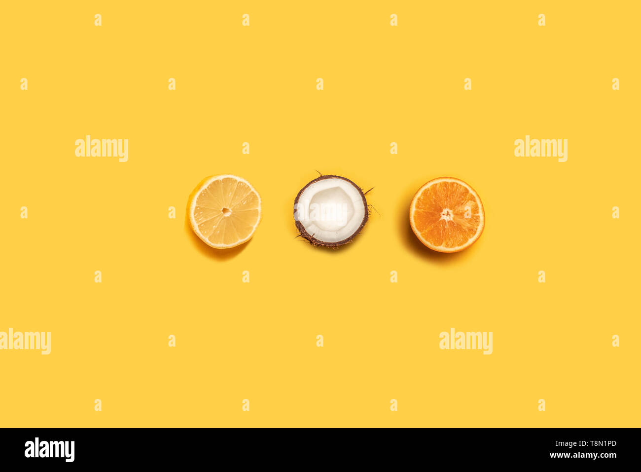 Lemon, orange and coconut on a yellow background Stock Photo - Alamy