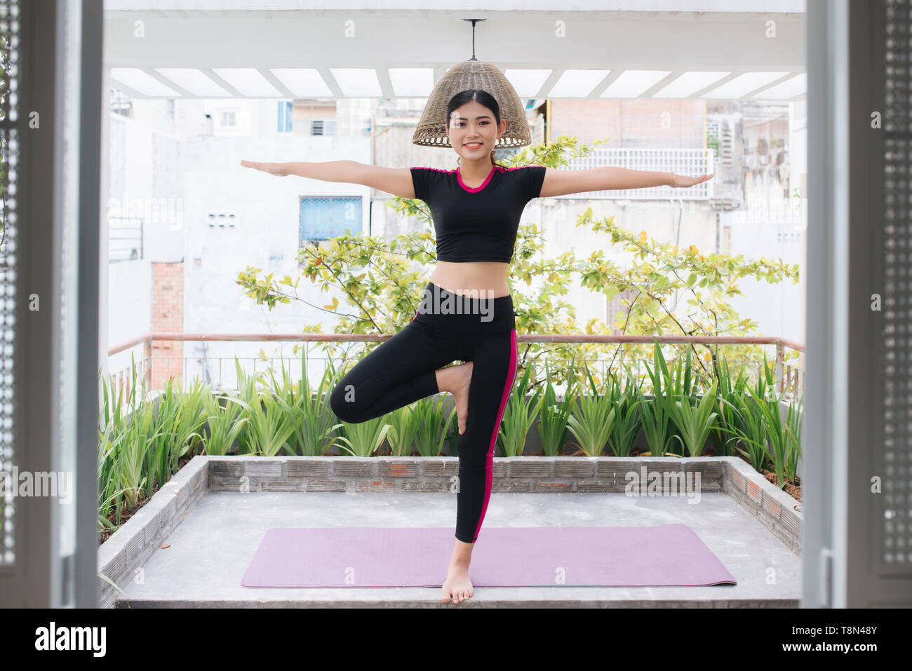 Young asian woman in relaxation stretching position on her balcony ...