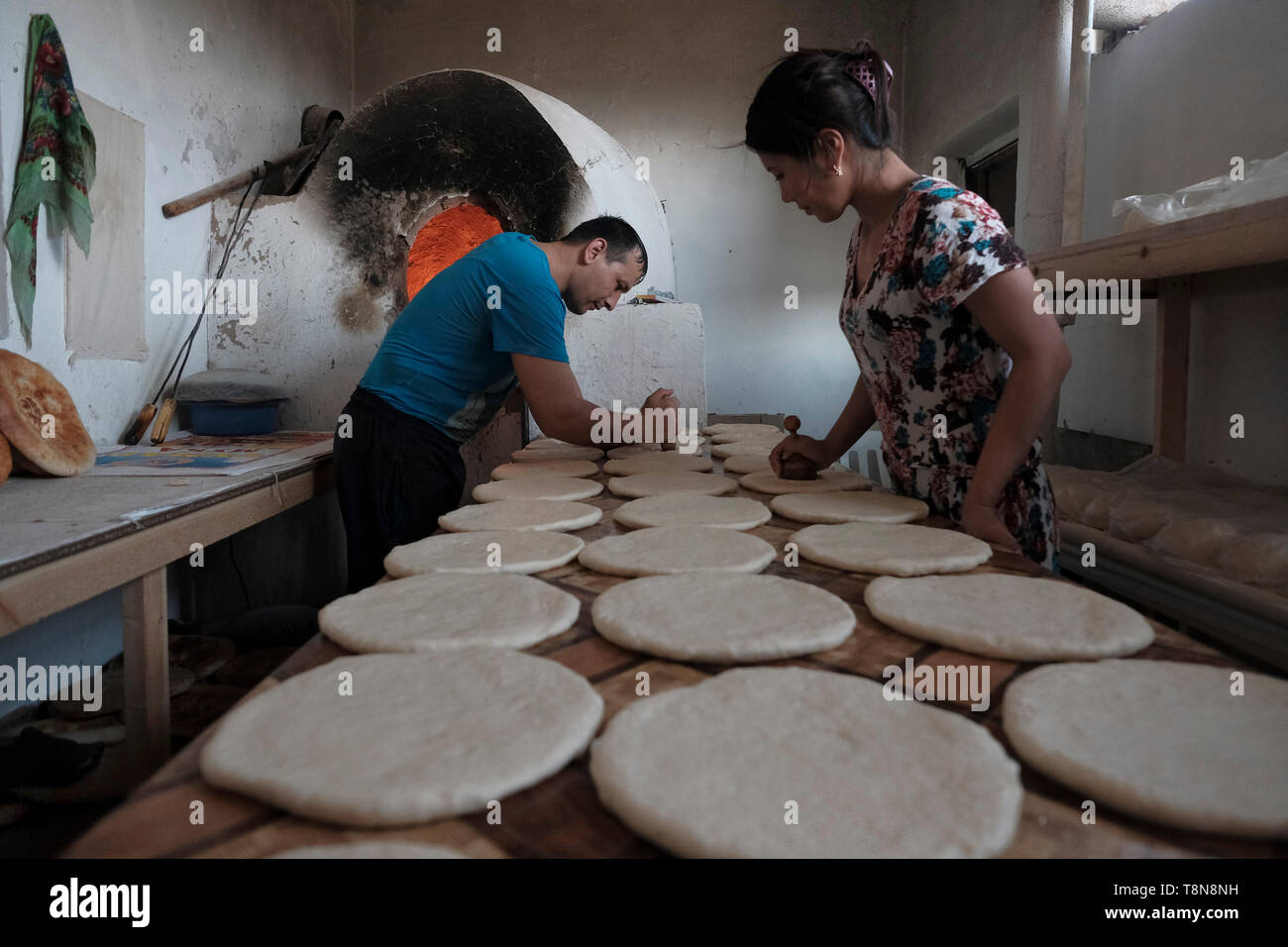 An Uzbek couple baking Naan oven-baked flatbread in the town of Mo‘ynoq ...