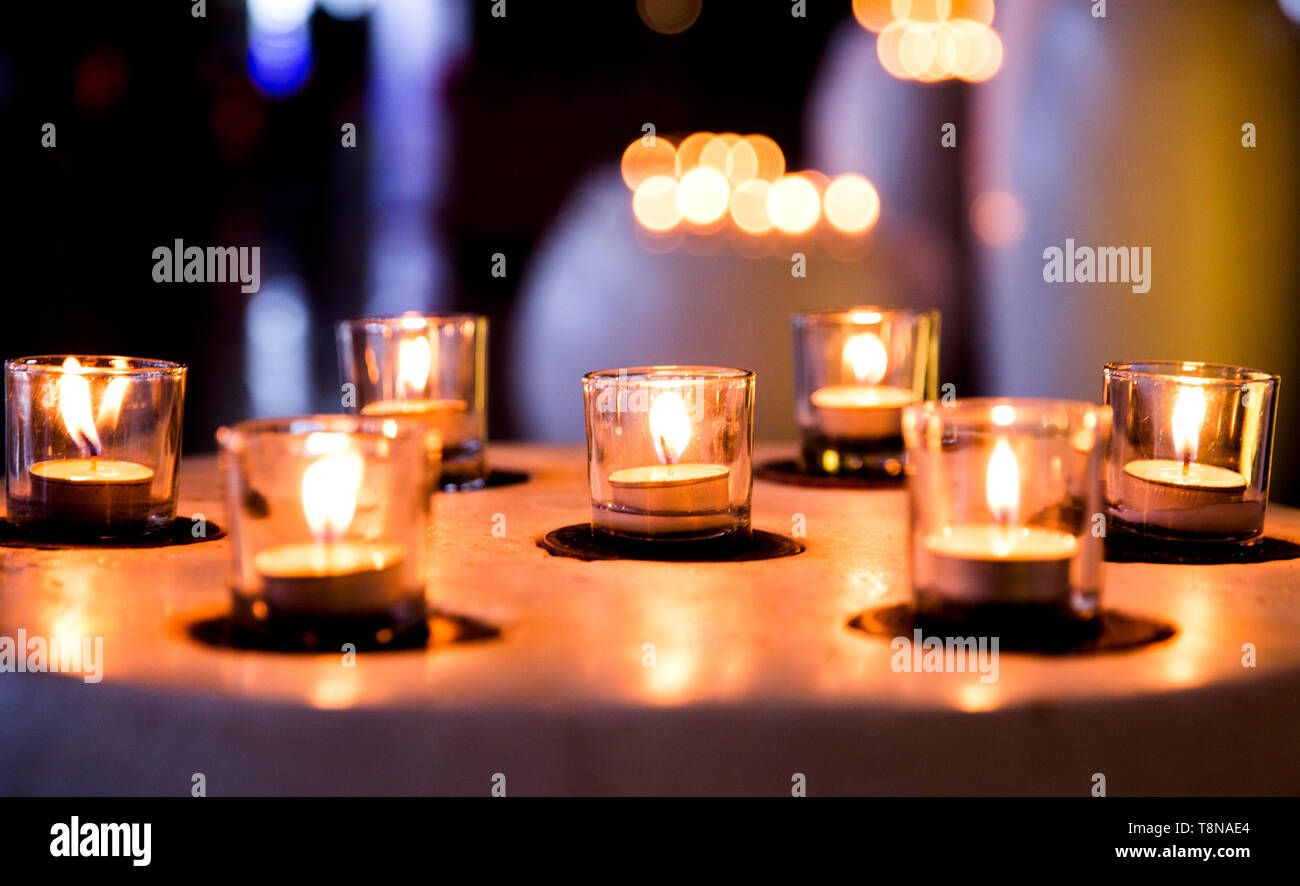 Flame of many candles burning on blurred lights background. Holiday ...