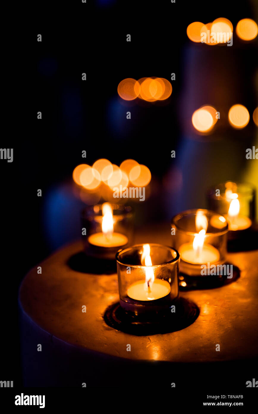 Flame of many candles burning on blurred lights background. Religion ...