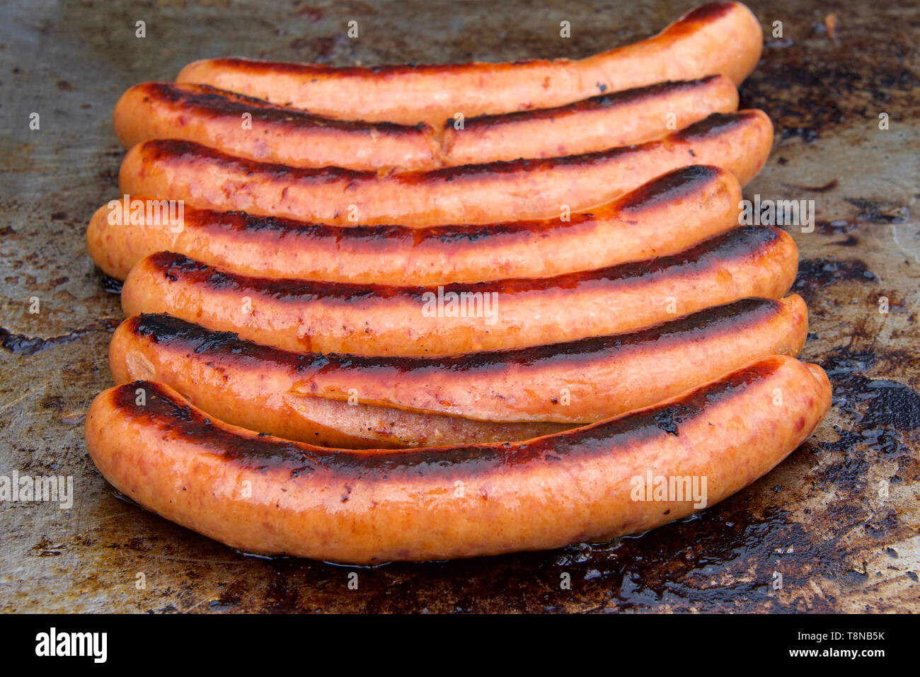 Close up on large sausages frying on an outdoor grill. Popular street ...