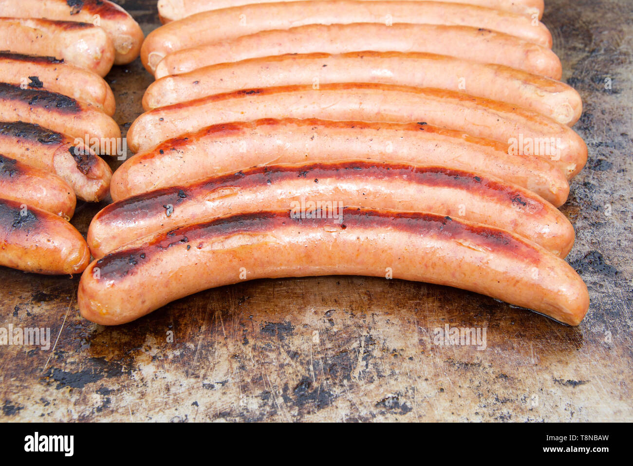 Close up on large sausages frying on an outdoor grill. Popular street ...