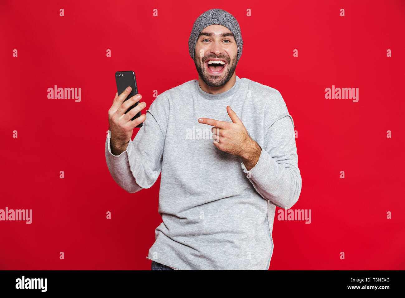 Image of attractive man 30s with beard and mustache holding smartphone ...
