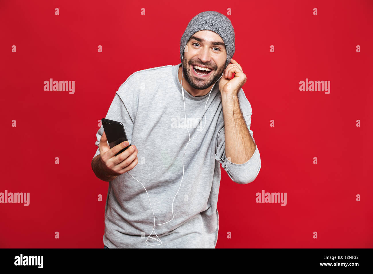Image of attractive man 30s listening to music using earphones and cell ...