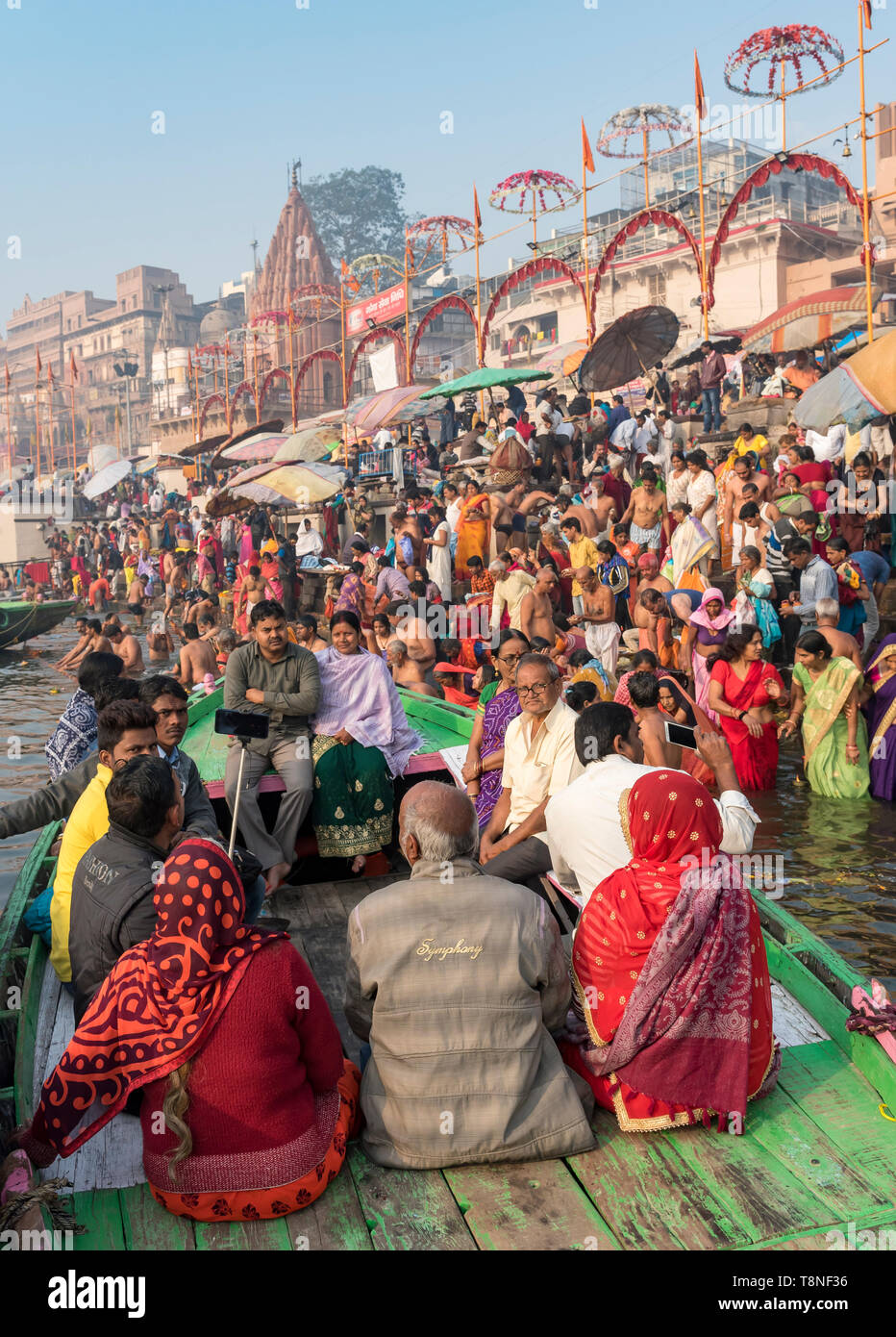 Tourists in a boat wath worshippers performing ritual bath and prayers ...